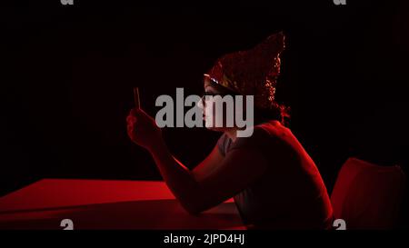 Paranoid caucasian woman using smartphone wearing tinfoil hat ...