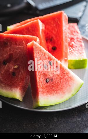 Slices of ripe watermelon on plate with a knife on white wooden ...