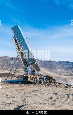 Landfill tipper lifts trailer container to a high angle to dump all the ...