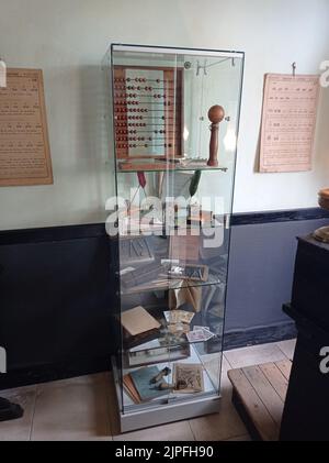 Une classe ancienne avec des bancs ,des affiches, des outils scolaires ...