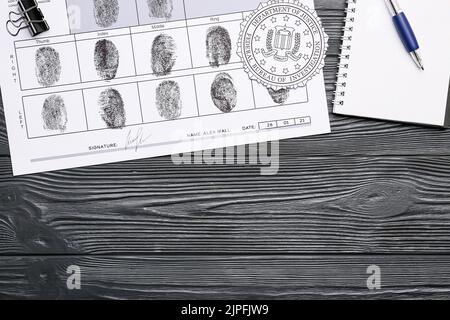 Paper sheet with finger prints, seal of FBI and notebook on dark wooden ...
