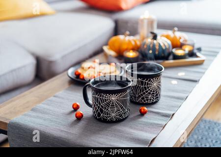 Cozy halloween plans at home. Hot tea drink in black mugs with spider ...