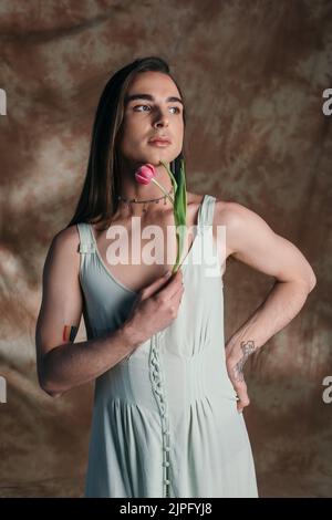 tattooed nonbinary man holding hand in pocket near queer friends in ...