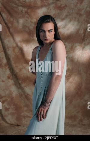 tattooed queer person looking at camera near elegant nonbinary friends ...