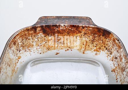 Glass pyrex oven dish used with burnt food on the edges on white ...