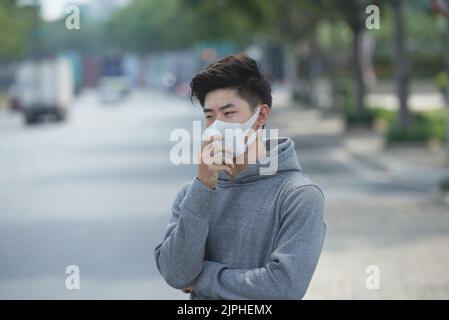 Sick Asian man in face mask walking outdoors Stock Photo - Alamy