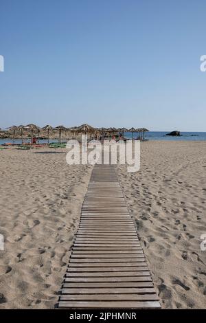 Wooden pathway leading to sun beds, sun umbrellas at the amazing beach ...