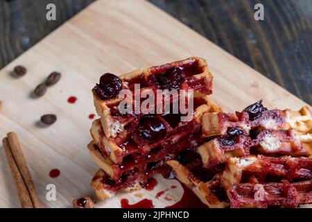 soft waffles with red cherry jam on a serving board, cooking with soft ...