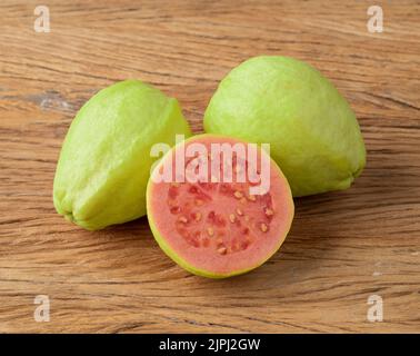 Red guavas with half fruit over wooden table Stock Photo - Alamy