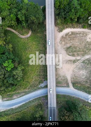 Downward aerial view of tropical river bridge with cars passing over ...