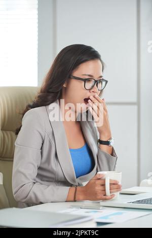 Beautiful Vietnamese business lady drinking coffee and reading e-mails ...