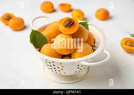 Colander full of ripe apricots on light background, closeup Stock Photo ...