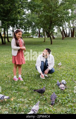 Girl feeding the pigeons in a park. Western Springs Park. Auckland ...
