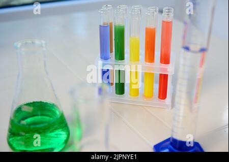 Graduated cylinder, bottles and test tubes in rack on mirror surface ...