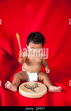 Happy Native American baby plays a traditional hand drum form the ...