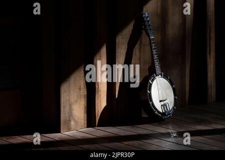 Classic Banjo-mandolin on a porch, sunlight producing dramatic shadows ...