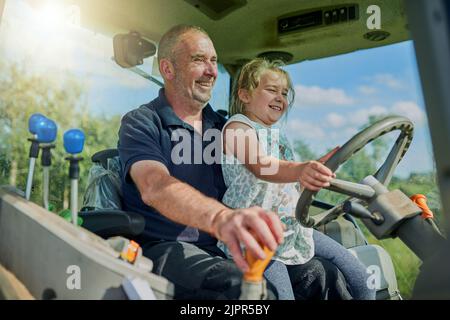 Farmer father riding tractor with his daughter. Girl growing up on ...
