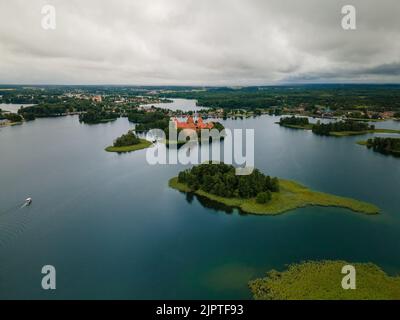 An aerial shot of the Trakai castle surrounded by green trees over the ...
