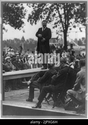Theodore Roosevelt standing on a table speaking to a seated audience ...