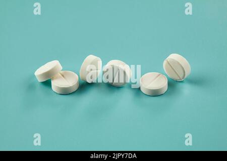 Six white tablets scattered on a cyan background Stock Photo - Alamy