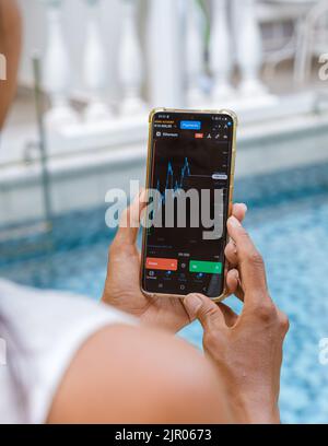 Asian women with hat check cryptocurrency on their phone when on ...