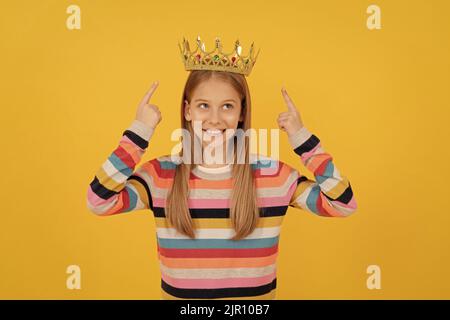 happy teen kid point finger on queen crown on yellow background. Child ...