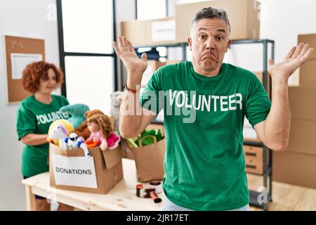 Middle age man wearing volunteer t shirt working with laptop relaxed ...