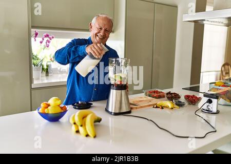 Senior man smiling confident pouring milk on blender at kitchen Stock ...