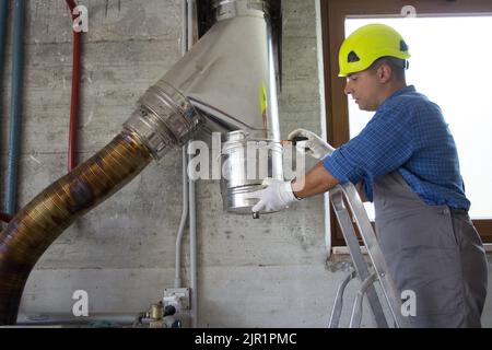 Image of a hard-hatted handyman plumber on a ladder repairing and ...