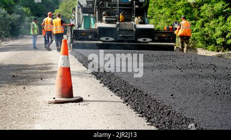 Workers use asphalt paving machines to lay asphalt on parking lot while ...
