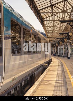 A train rests beside a railway station platform. There are passenger in ...