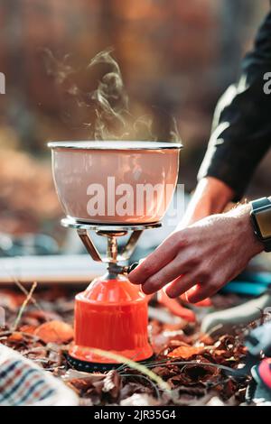 Male hand preparing soup on portable gas stove Stock Photo - Alamy