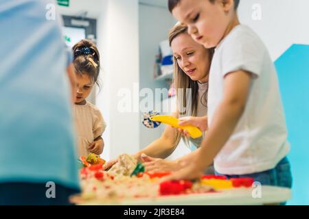 teacher and kids playing with kinetic sand in the kindergarten. High ...