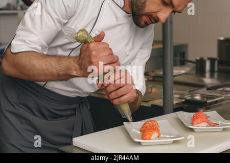 Sushi master prepares sushi for serving in modern commercial kitchen ...