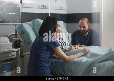 Considerate parents sitting beside hospitalized sick little daughter ...