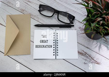 Notepad with brown envelop, reading glasses, pen and potted plant on ...