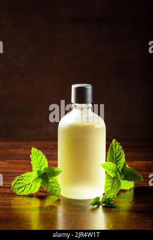 A dark bottle of essential oil with fresh eucalyptus leaves on a wooden ...