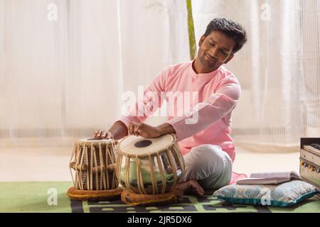 Portrait of young man playing Tabla at home Stock Photo - Alamy