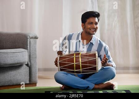 Portrait of young man playing Dholak at home Stock Photo - Alamy