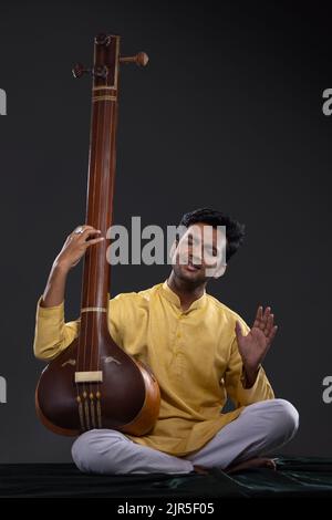 Portrait of young man performing with Tanpura at concert Stock Photo ...