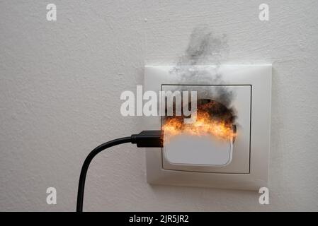 burning wall electrical socket with plugged appliance cable from short ...