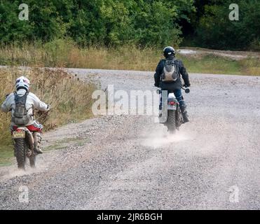 two motor cyclists (bikers) riding their off-road motorbikes along a ...