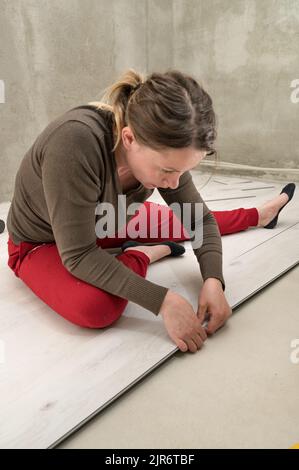 Installation of quartz vinyl floor, female master installs the floor ...