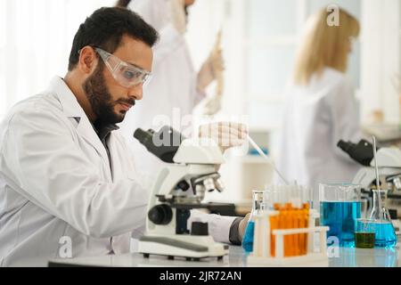 scientist doing research on plants holding a green solution in a test ...