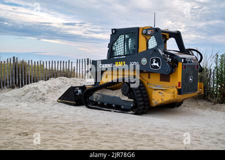 A Deere 325G track loader moves beach sand in an effort to repair tidal ...