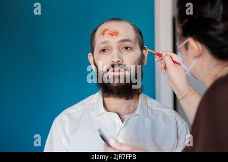 Artist using makeup effects to create zombie costume and scary dramatic ...