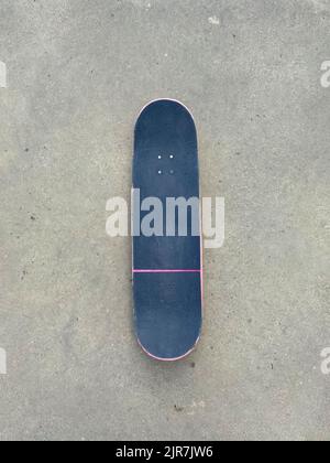 Scrached up pink skateboard laying on smooth concrete surface at local ...