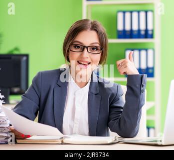 Young female employee very busy with ongoing paperwork in time ...