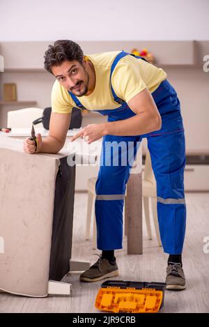 Young carpenter repairing arm-chair at home Stock Photo - Alamy