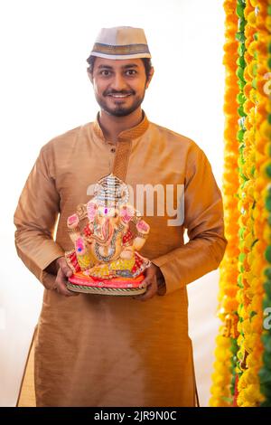 Portrait of a Maharashtrian man carrying statue of Lord Ganesh Stock ...